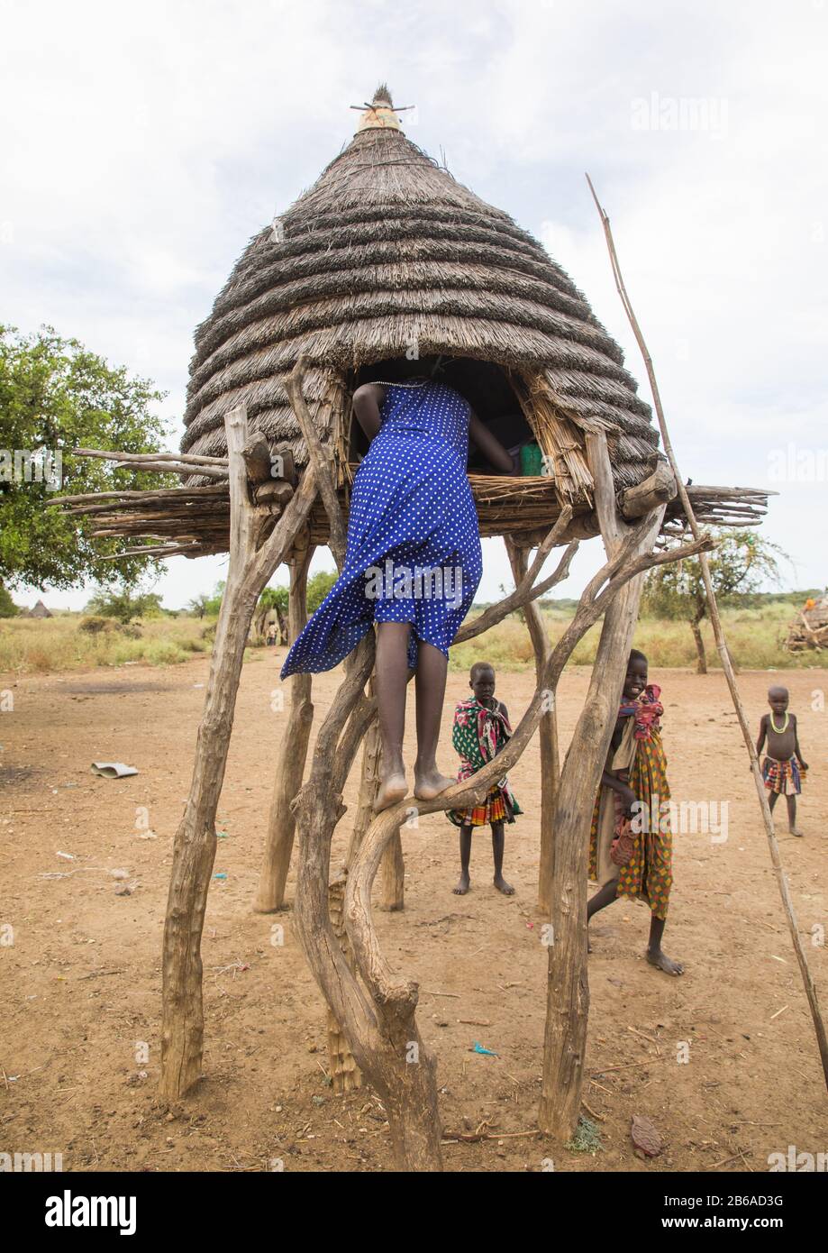 Toposa tribe girl climbing in a granary in a village, Namorunyang State ...
