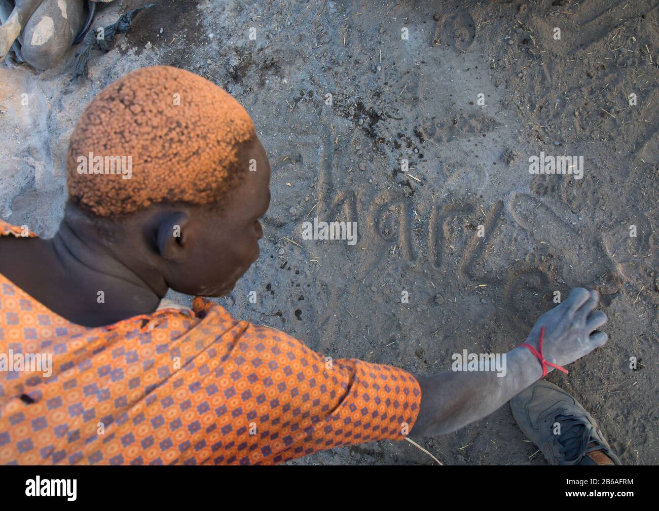 Mundari tribe man with hair dyed in orange with cow urine writing his ...