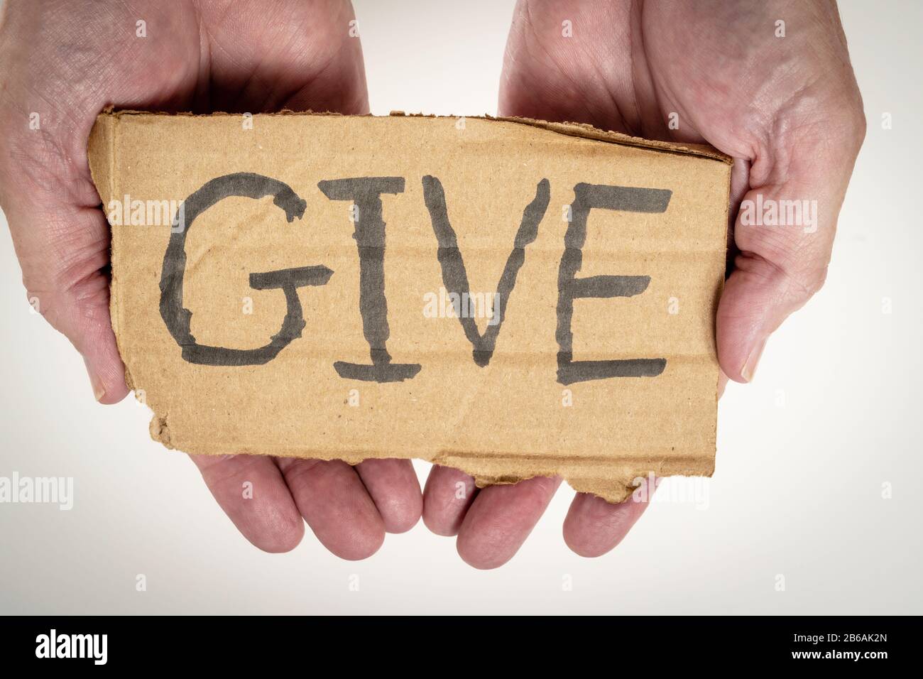 A cardboard sign in palm of hands with the word give. Generosity theme ...