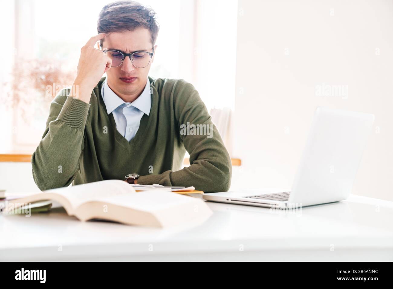 Photo of stressed tired young guy student sit at the table indoors ...