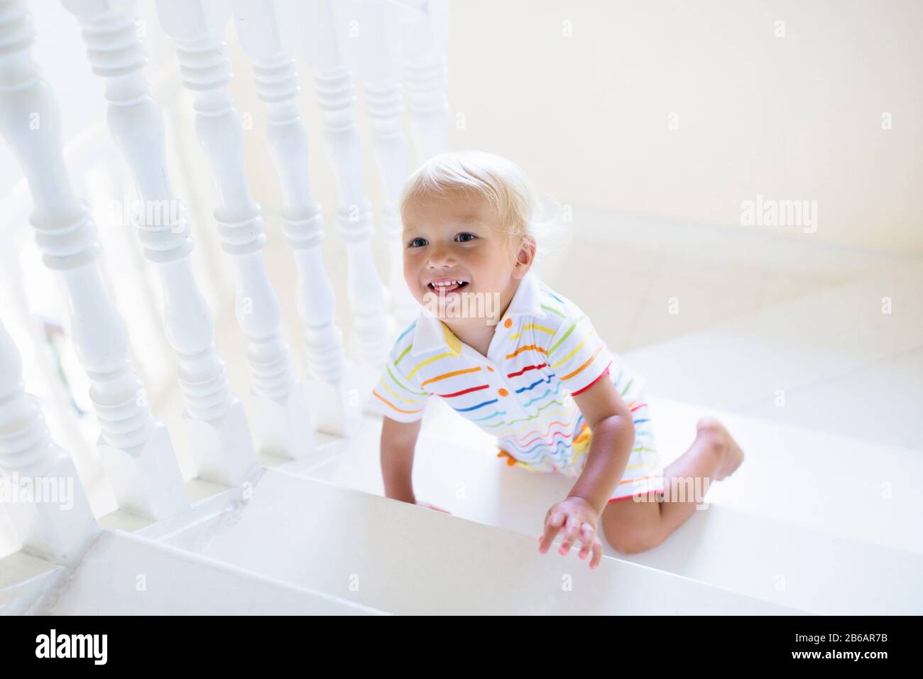 Kid walking stairs in white house. Baby boy playing in sunny staircase ...