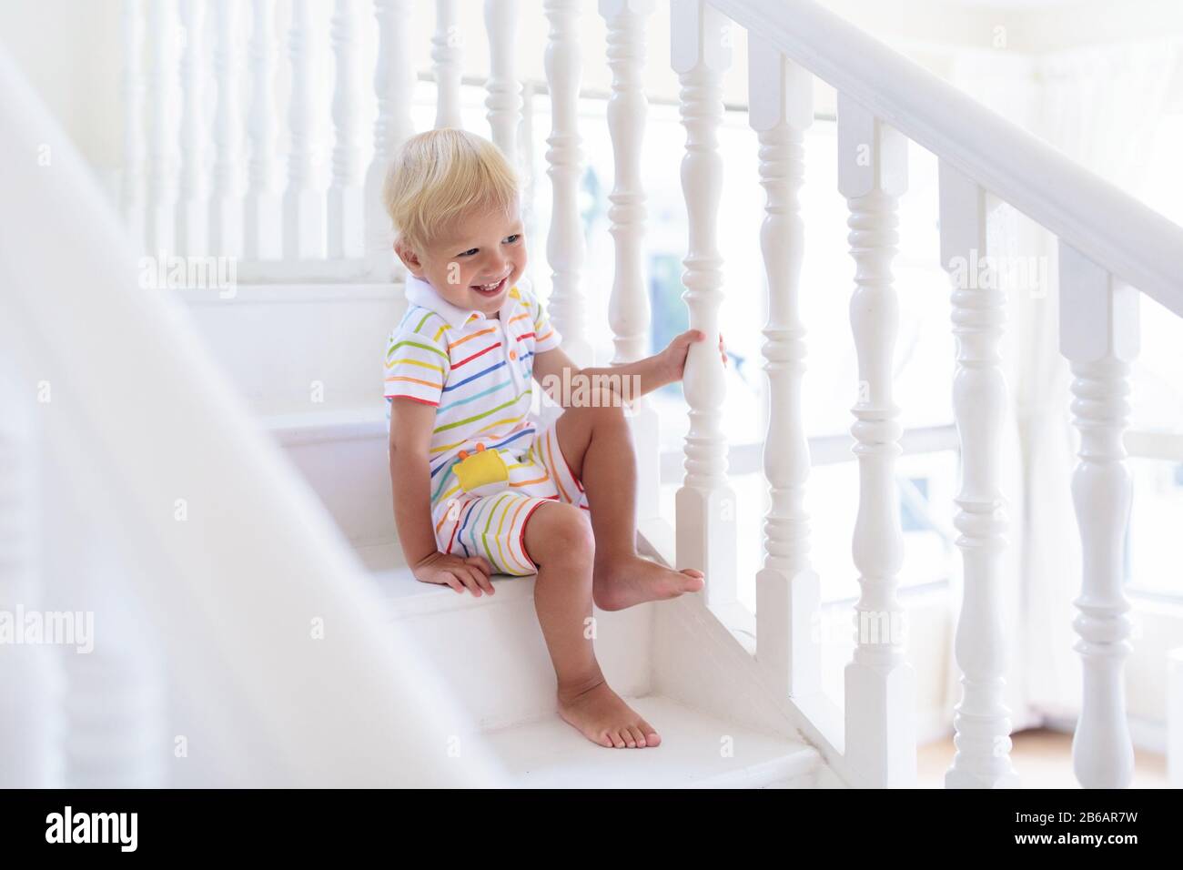 Kid walking stairs in white house. Baby boy playing in sunny staircase ...