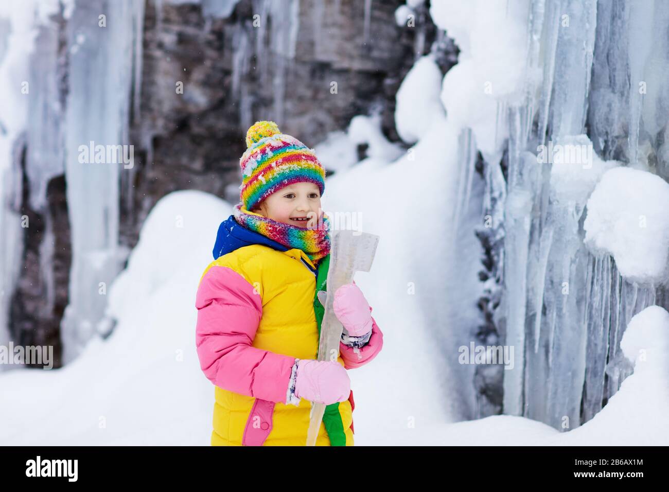 Children play with icicle in snow. Kids lick icicles at frozen mountain ...