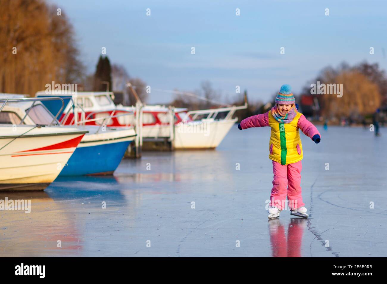 Child ice skating on frozen canal with wind mills and snow in Holland ...