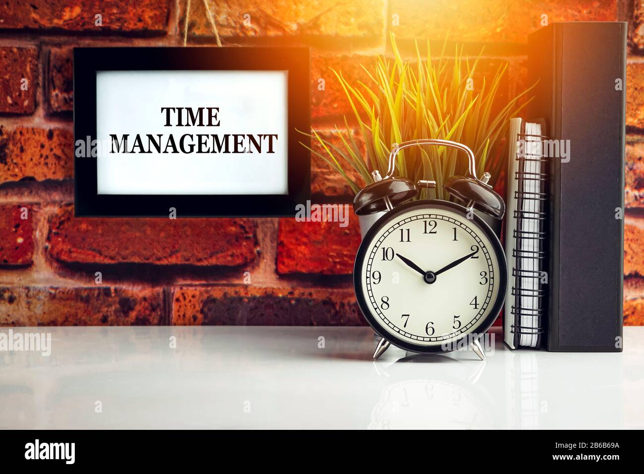 TIME MANAGEMENT text with alarm clock, books and vase on brick ...