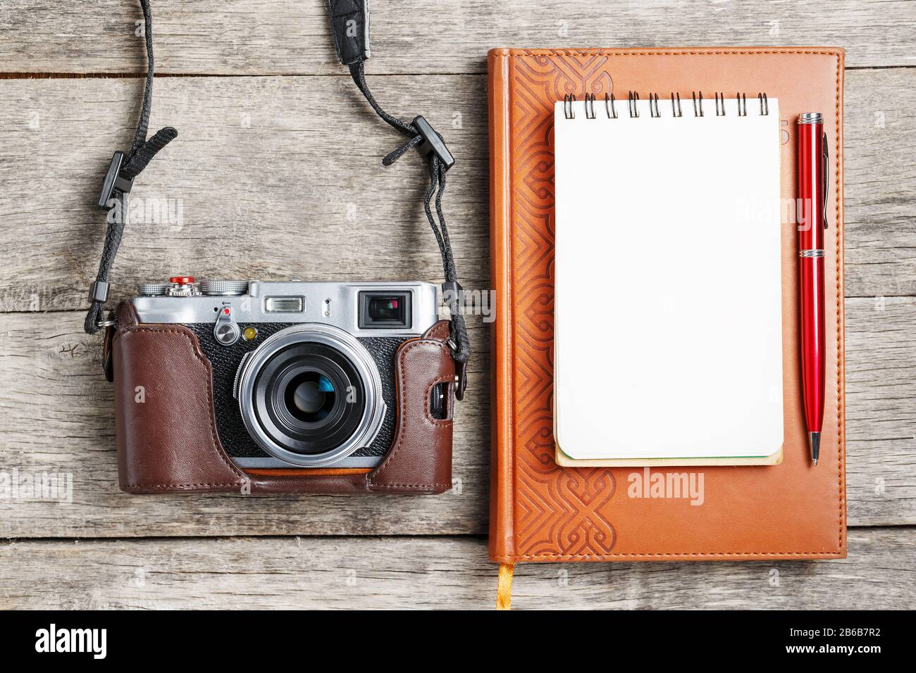 Classic camera with blank notepad page and red pen on gray wooden ...