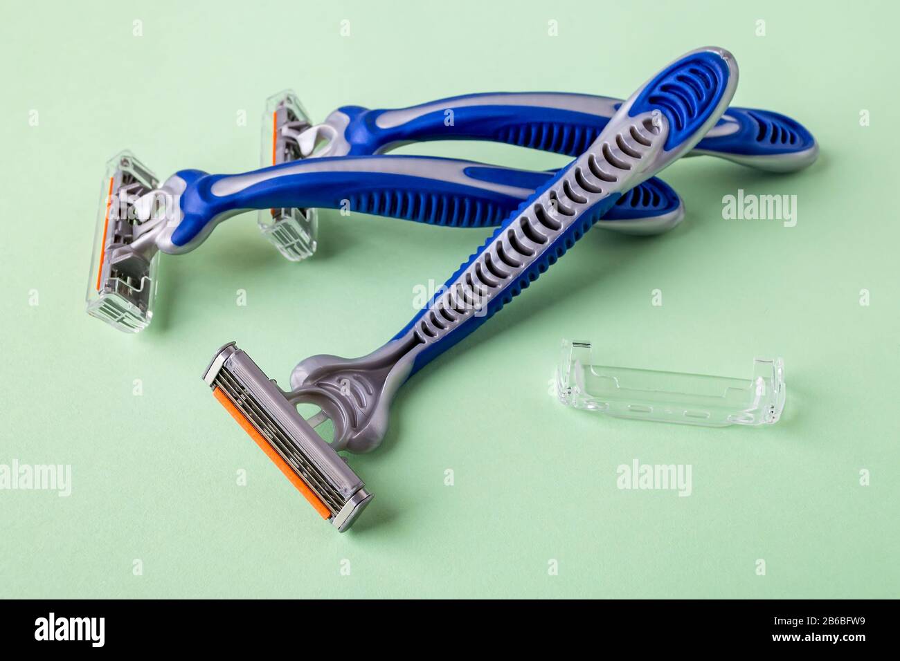 Three new disposable shaving razors with triple blade on a pastel green ...
