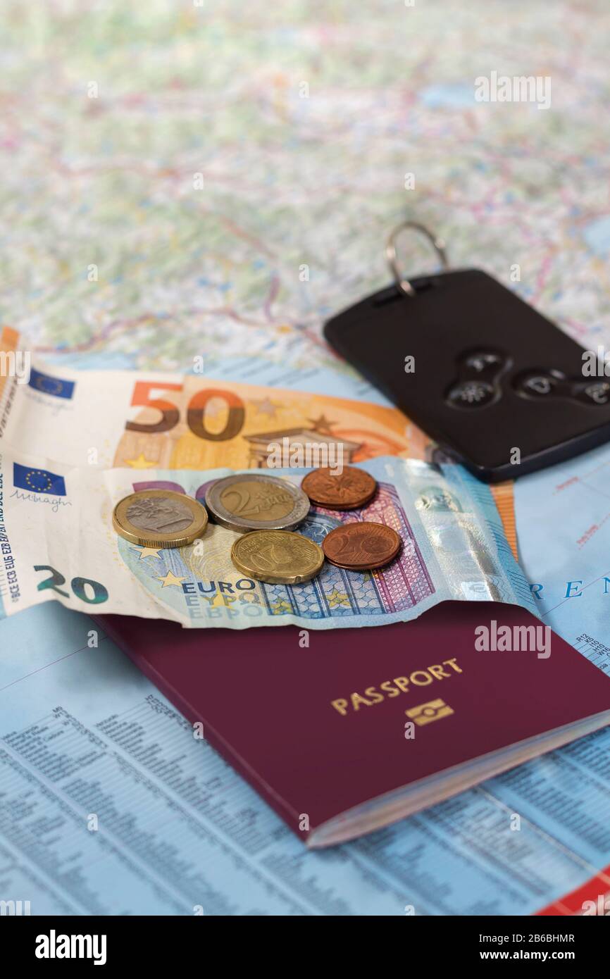 Euro banknotes and coins lie on the road map. The passport and car keys ...