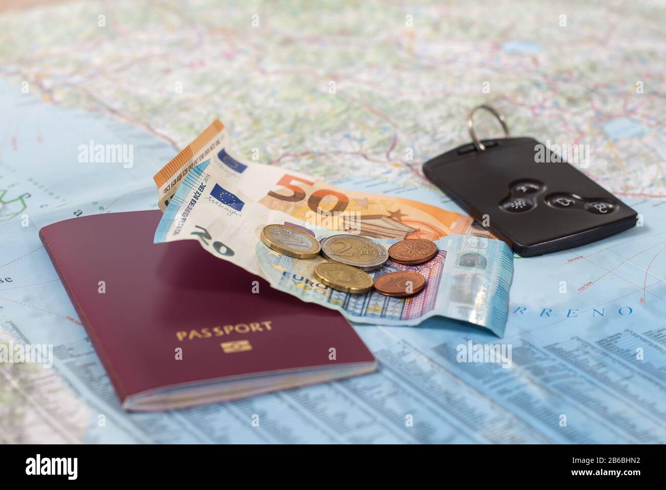A paper road map with a passport, euro banknotes and coins and a car ...