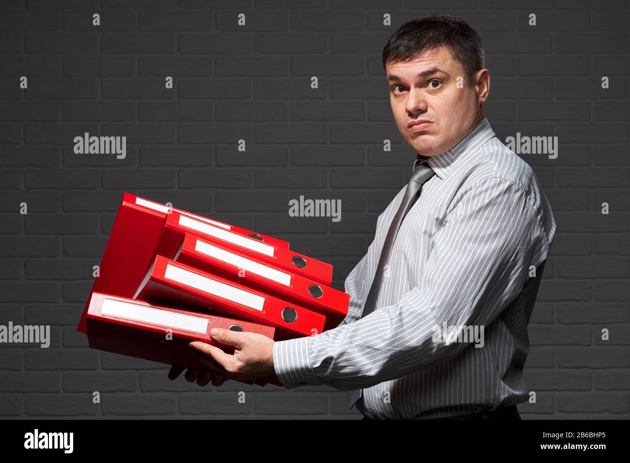 Very busy businessman closeup portrait, posing with red folders ...