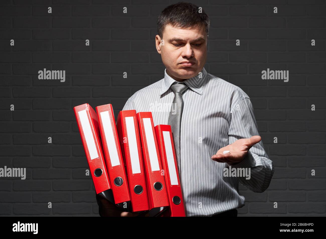 Very busy businessman closeup portrait, posing with red folders ...