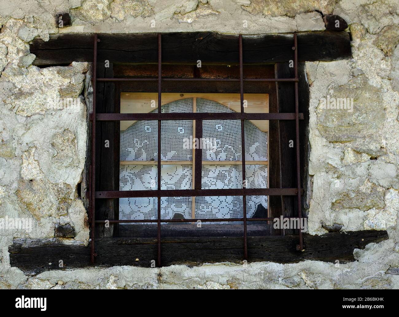Small square window at old stone house with lace and window bars Stock ...