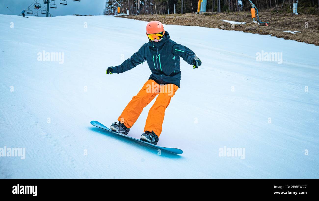Young man having fun going down the slope on a snowboard Stock Photo ...
