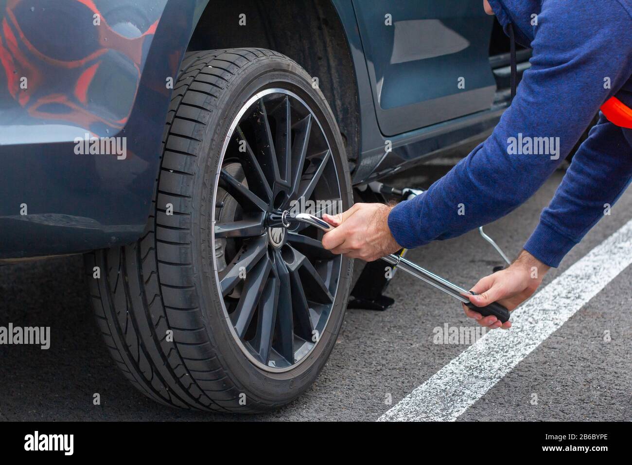 Close up mans hands changing a wheel using screwdriver. Replacing ...