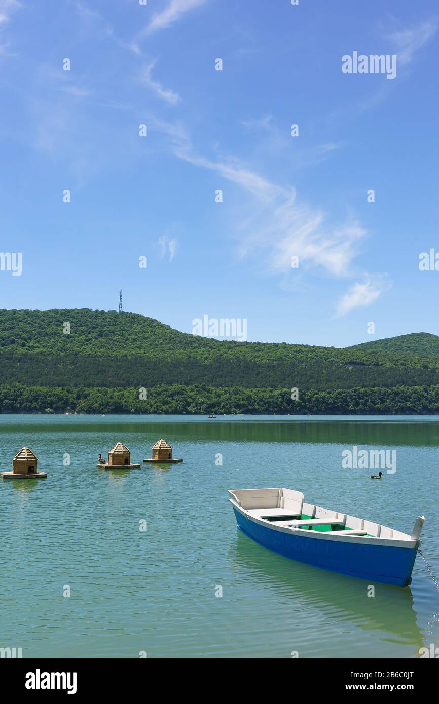 Bright blue empty rowing boat for riding on the green water of the ...