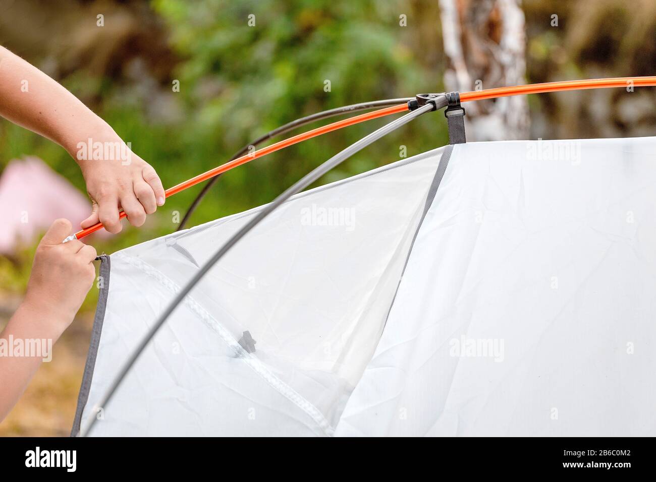 tourist setting a tent on the camping. Close up man's hands holding an ...
