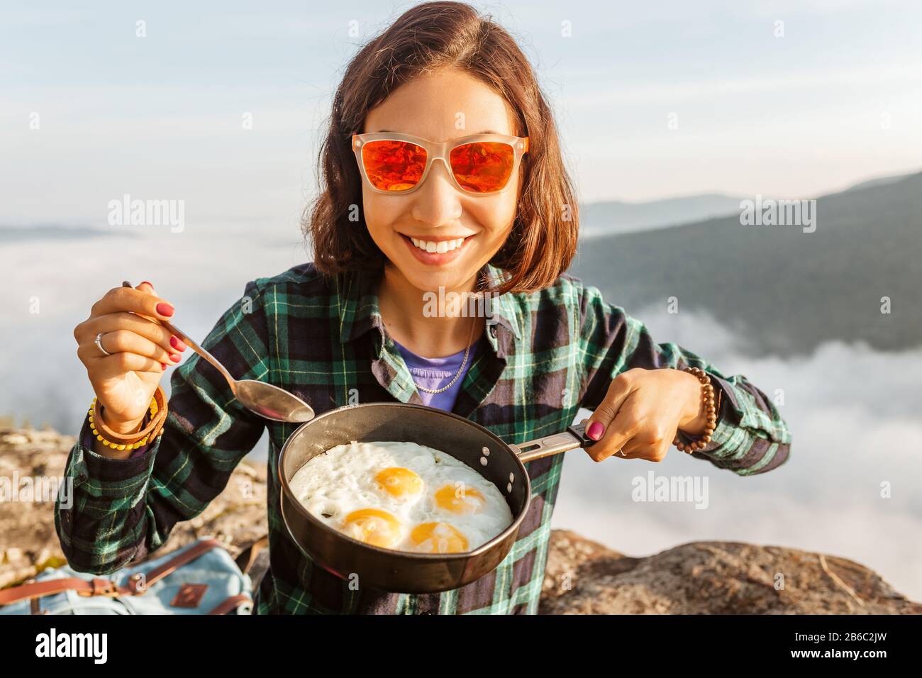 A woman traveler cooking and eating breakfast scrambled eggs and coffee ...