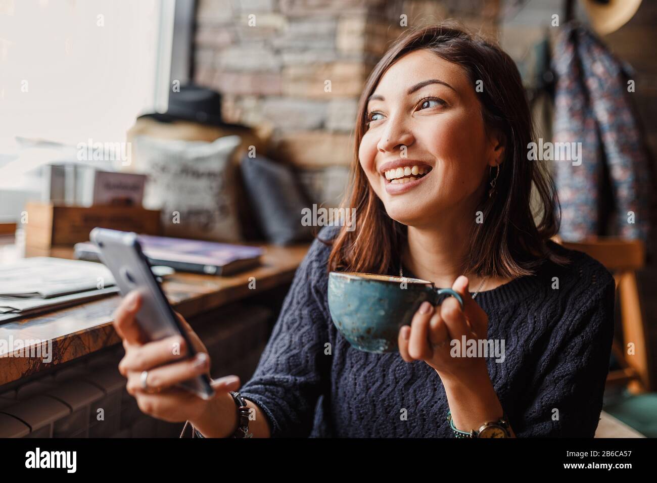 Young charming asian woman calling with cell phone while sitting alone ...