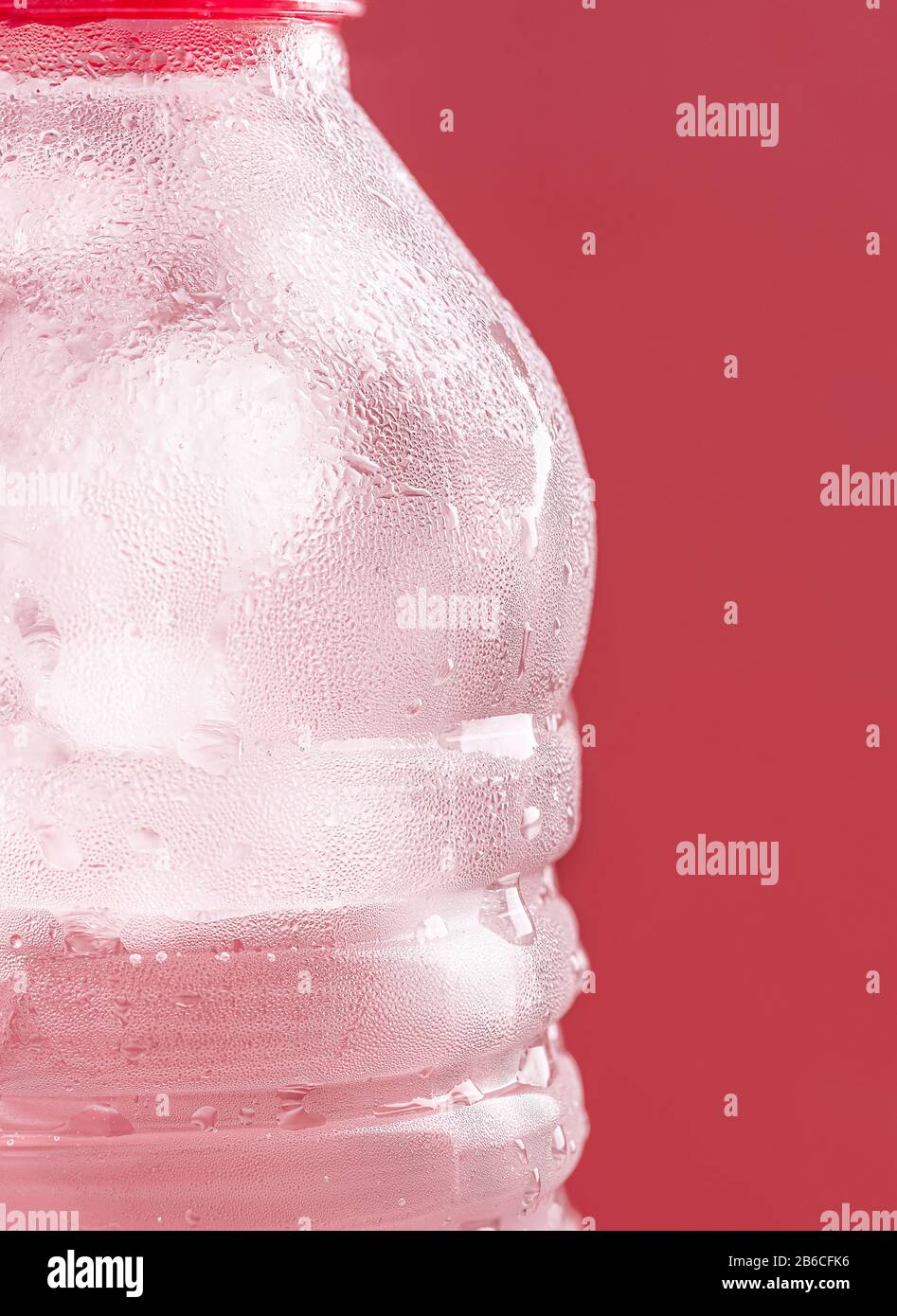 Cold water with ice in a plastic bottle on a pink background. Frosted ...