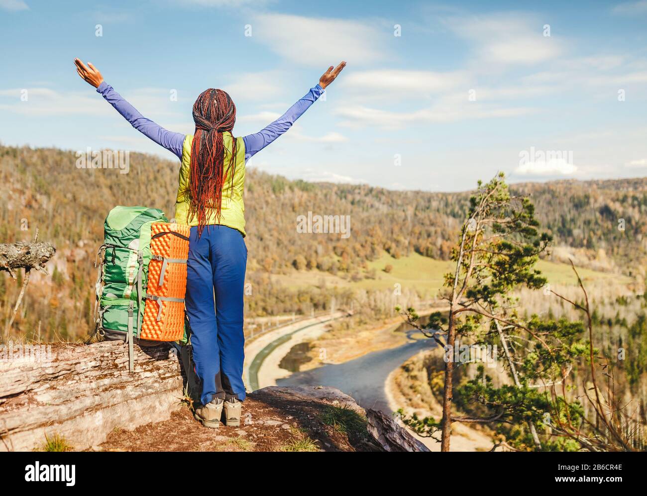 Young hippie girl with afro dreadlocks with backpack hiking in the wild ...