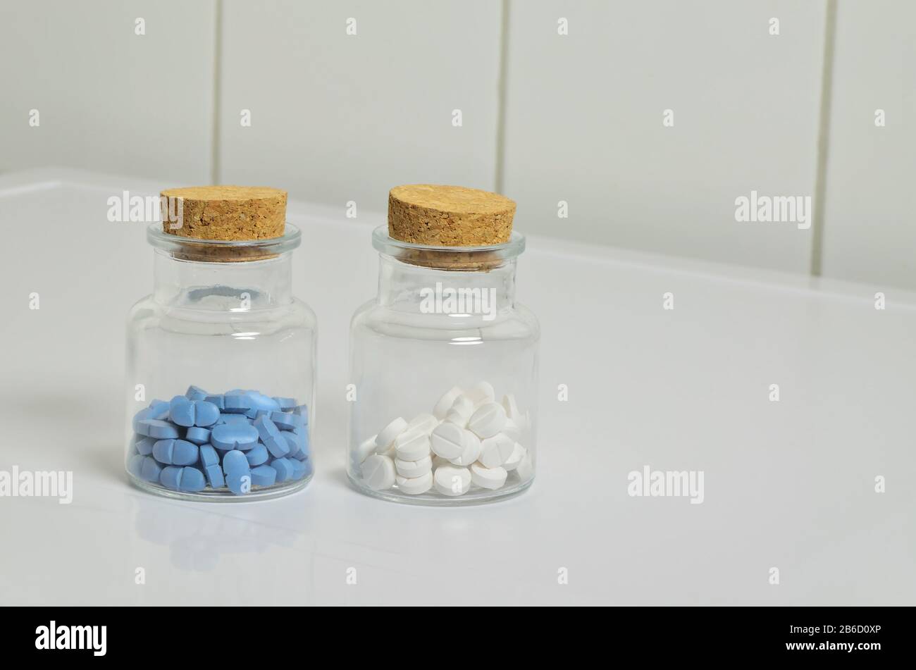 two vials with white and blue pills, close up, isolated on white ...
