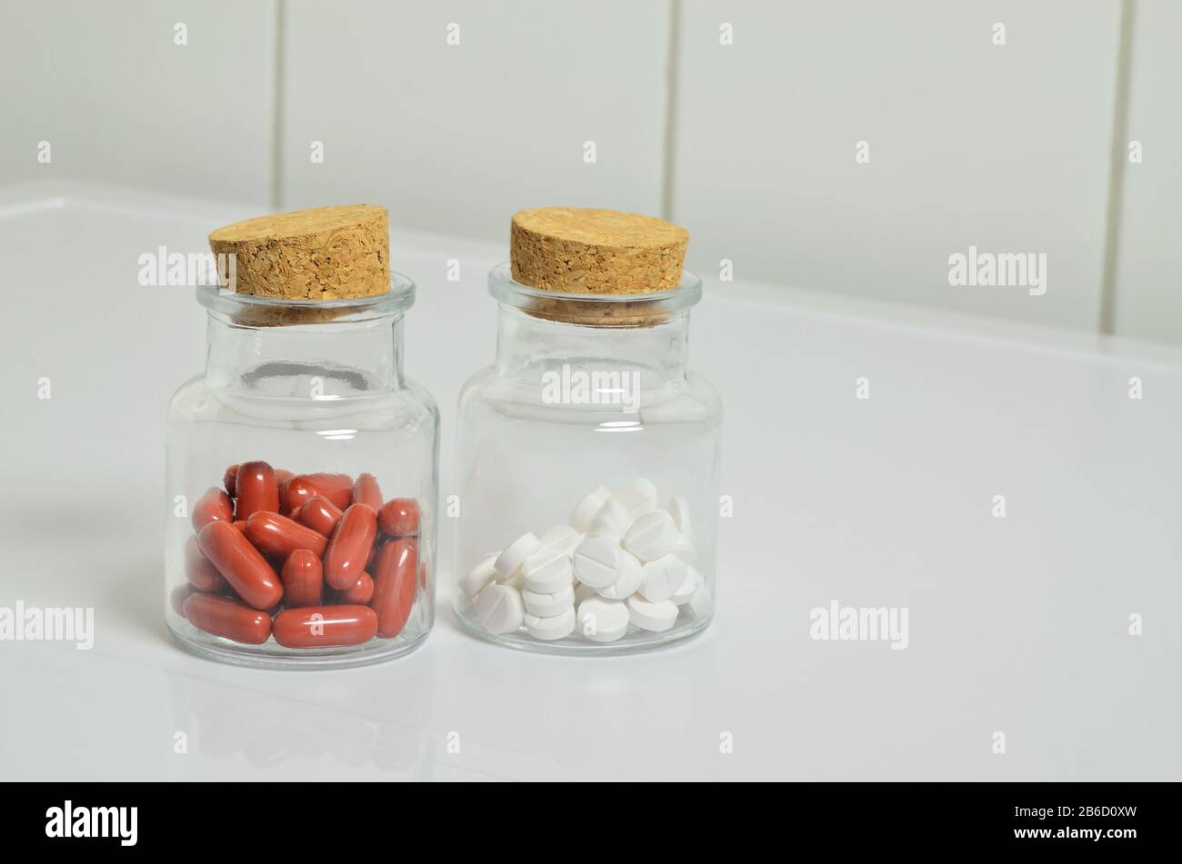 two vials with white and red pills, close up, isolated on white ...