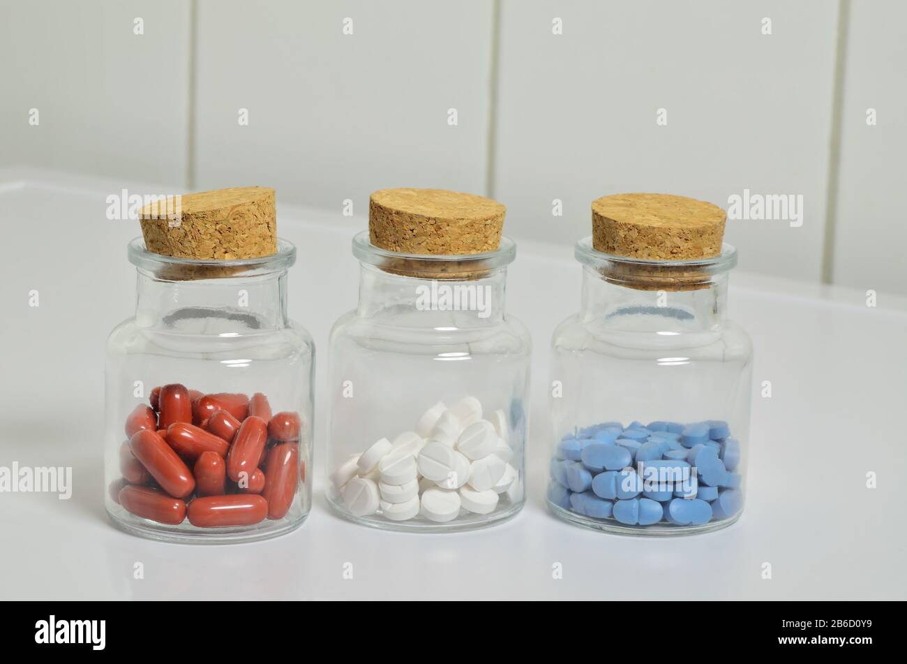three vials with red, white and blue pills, close up, isolated on white ...