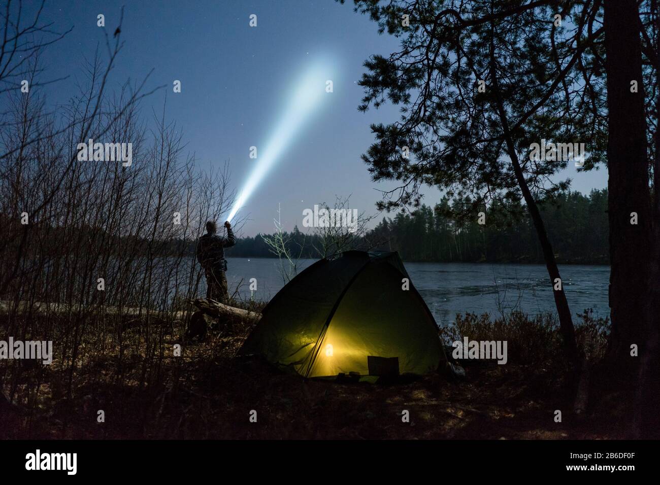 Man standing outdoor at dark night shining with flashlight. Mystical ...