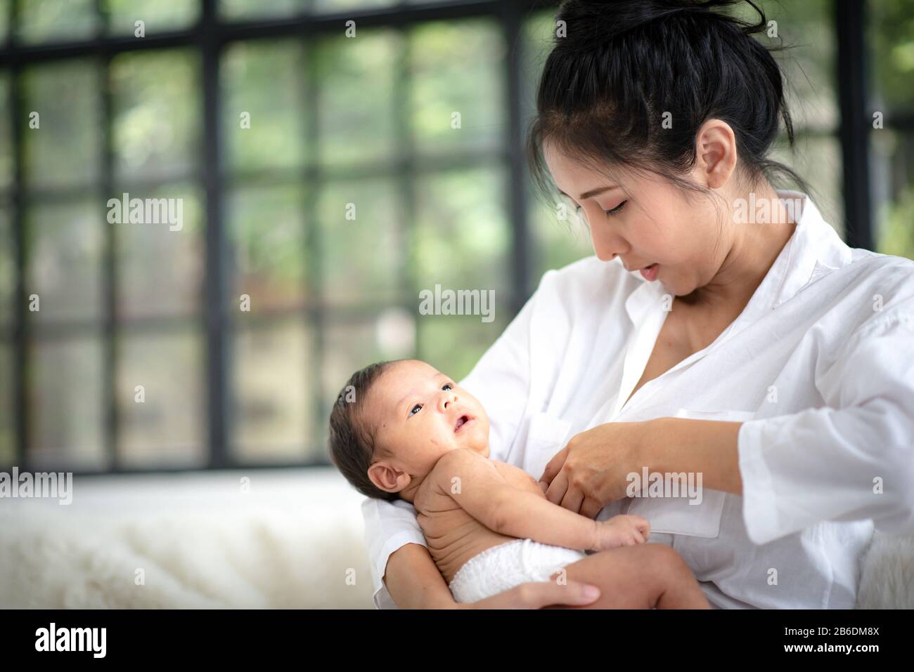 Adolescent mother is breastfeeding a baby Stock Photo - Alamy