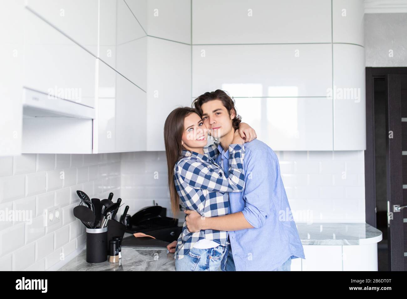 Cute couple hugging while cooking in their kitchen Stock Photo - Alamy