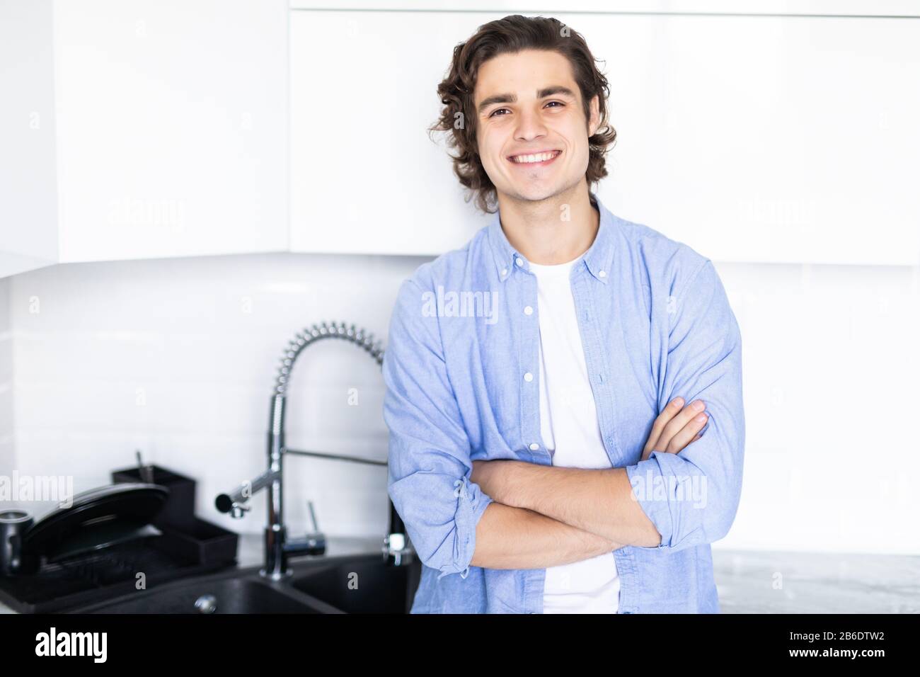 Portrait of confident young man standing by kitchen counter Stock Photo ...