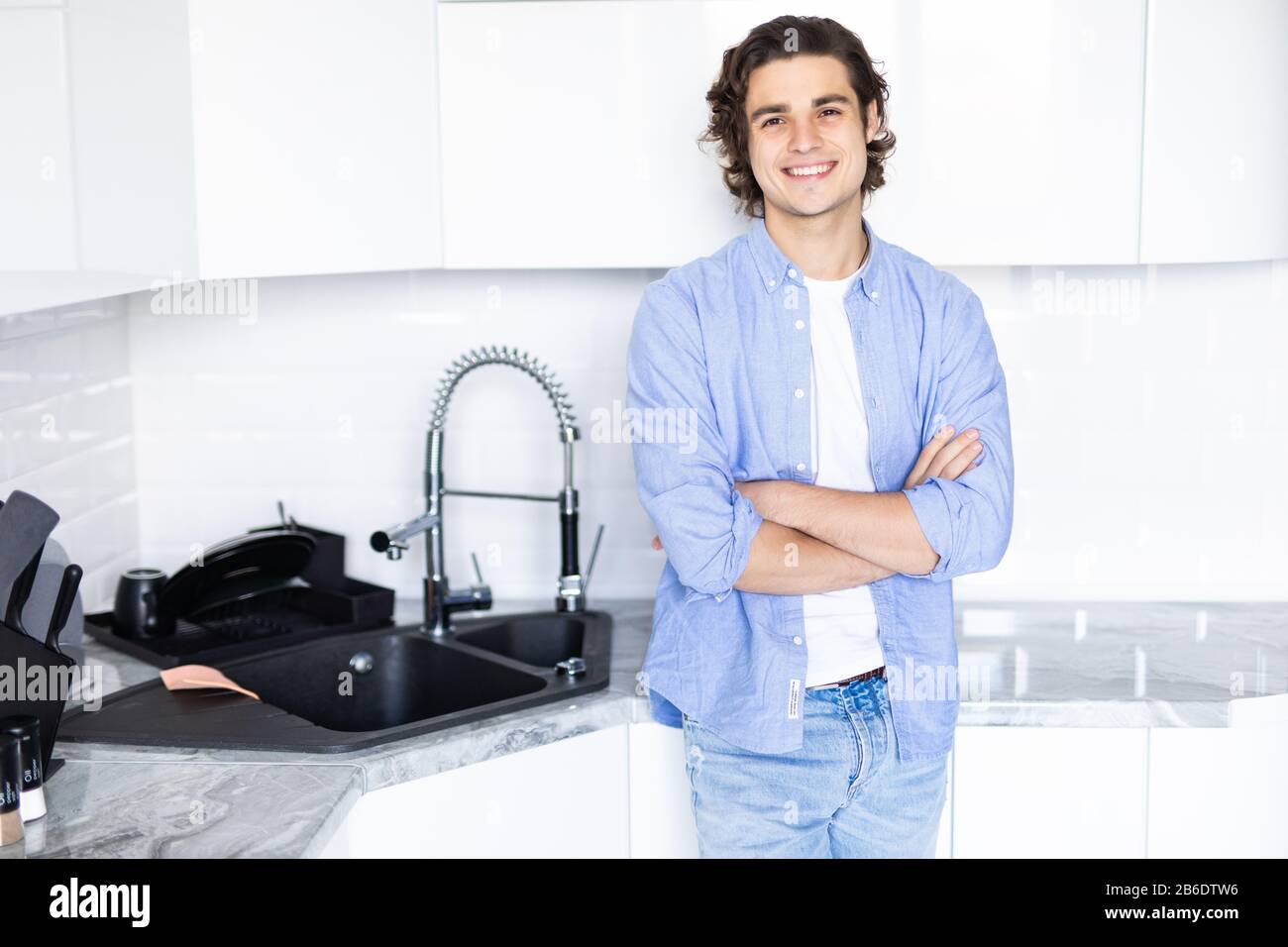 Portrait of confident young man standing by kitchen counter Stock Photo ...