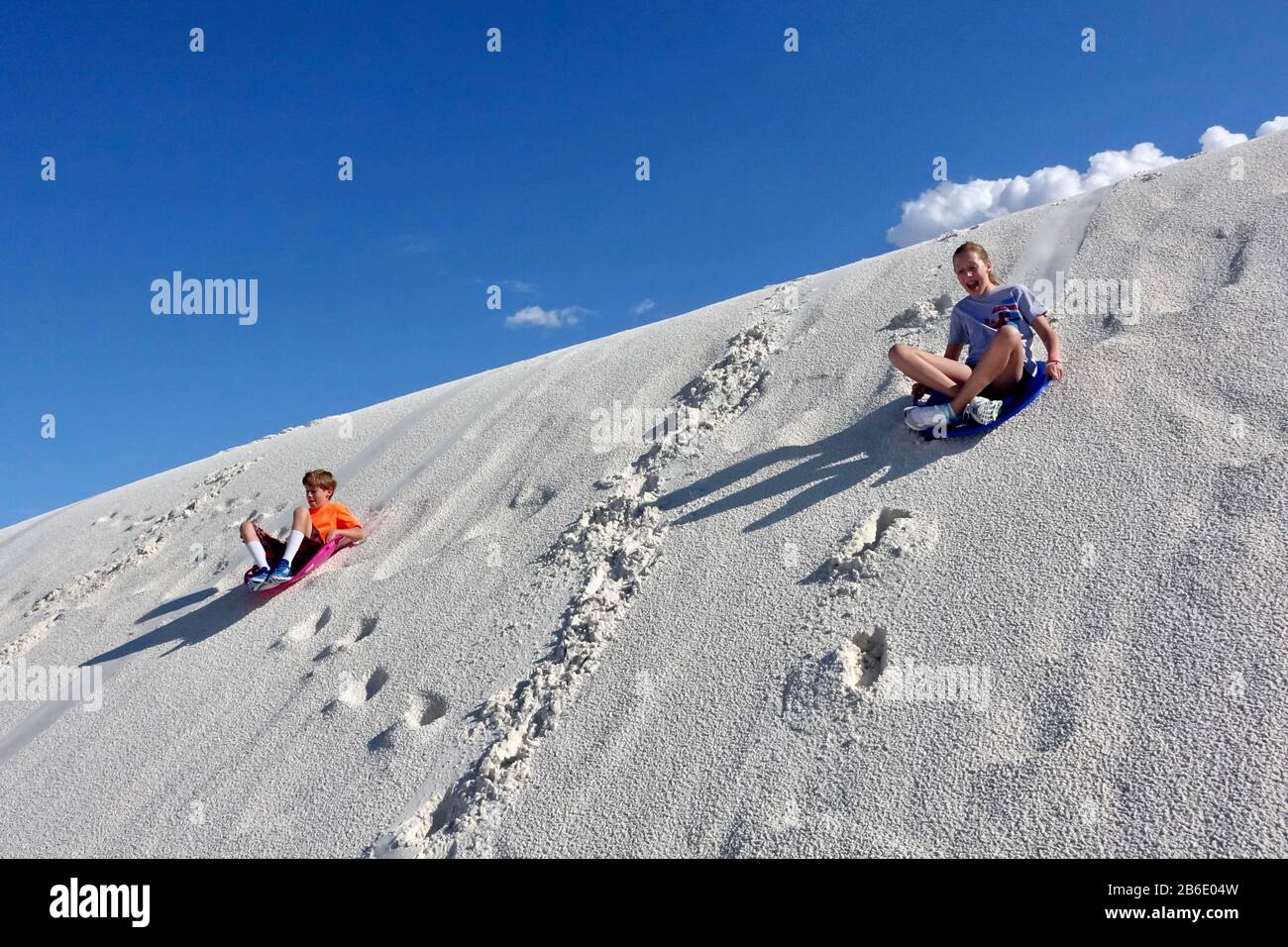 A boy and girl go sand sledding at White Sands, New Mexico Stock Photo ...