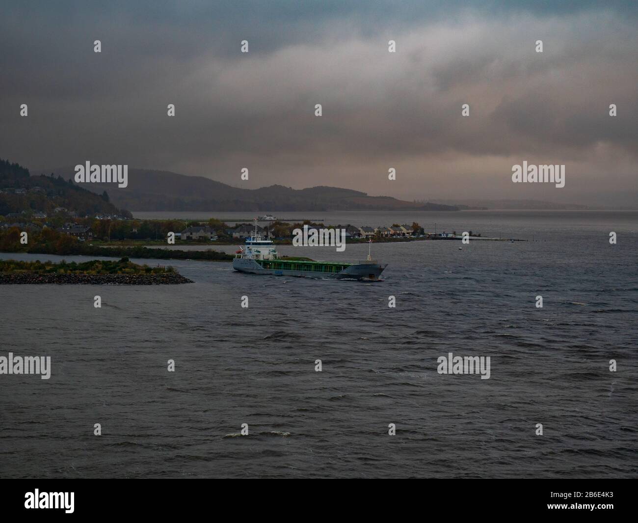 A cargo ship leaves port of Inverness on the river ness, Scotland, UK ...