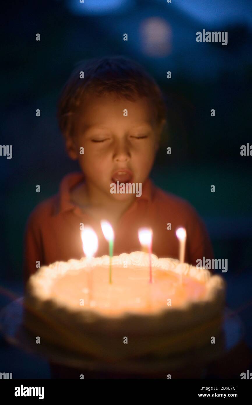 Young boy blowing out birthday candles Stock Photo - Alamy