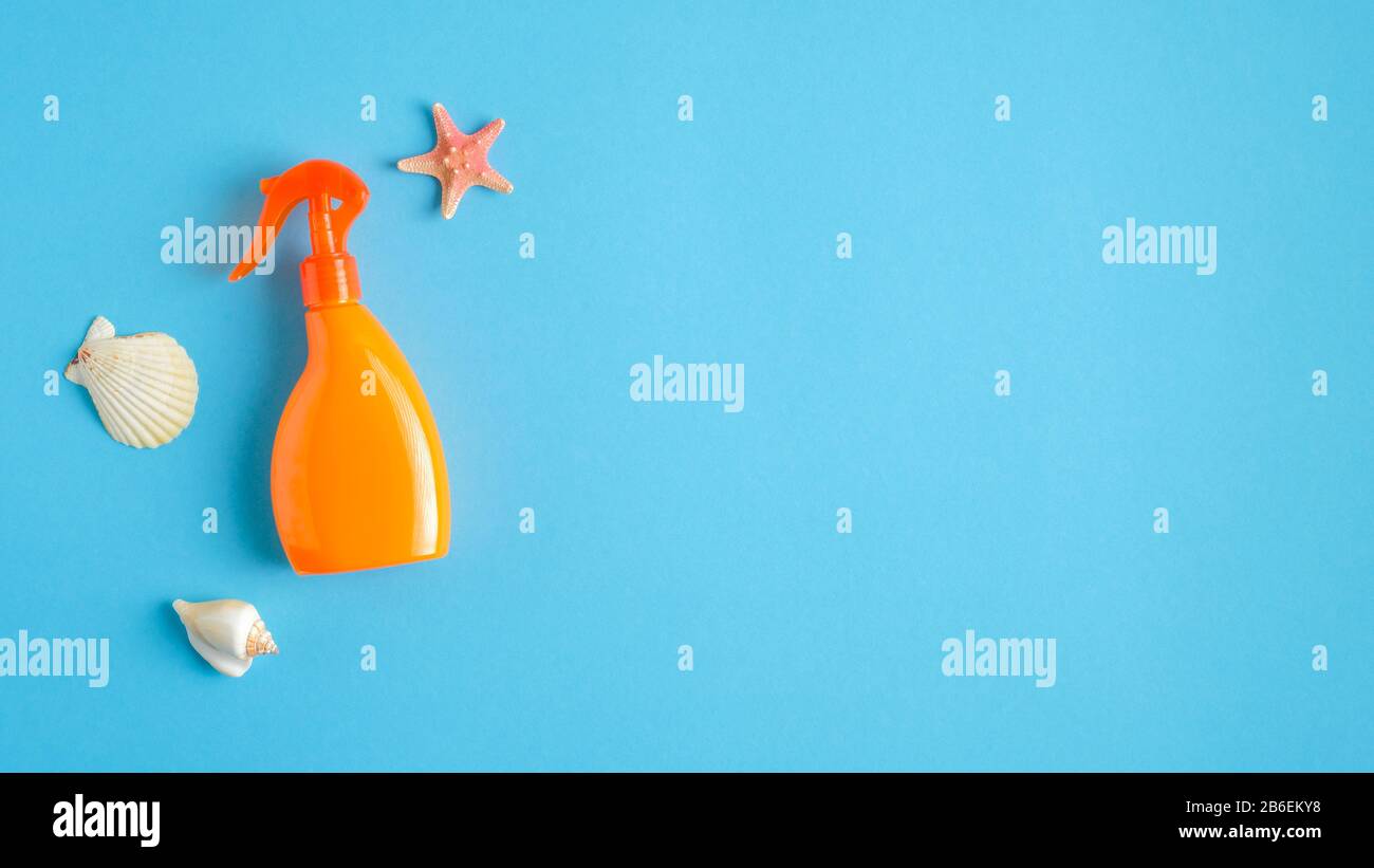 Orange sunscreen spray bottle and seashell on blue background. Sun ...