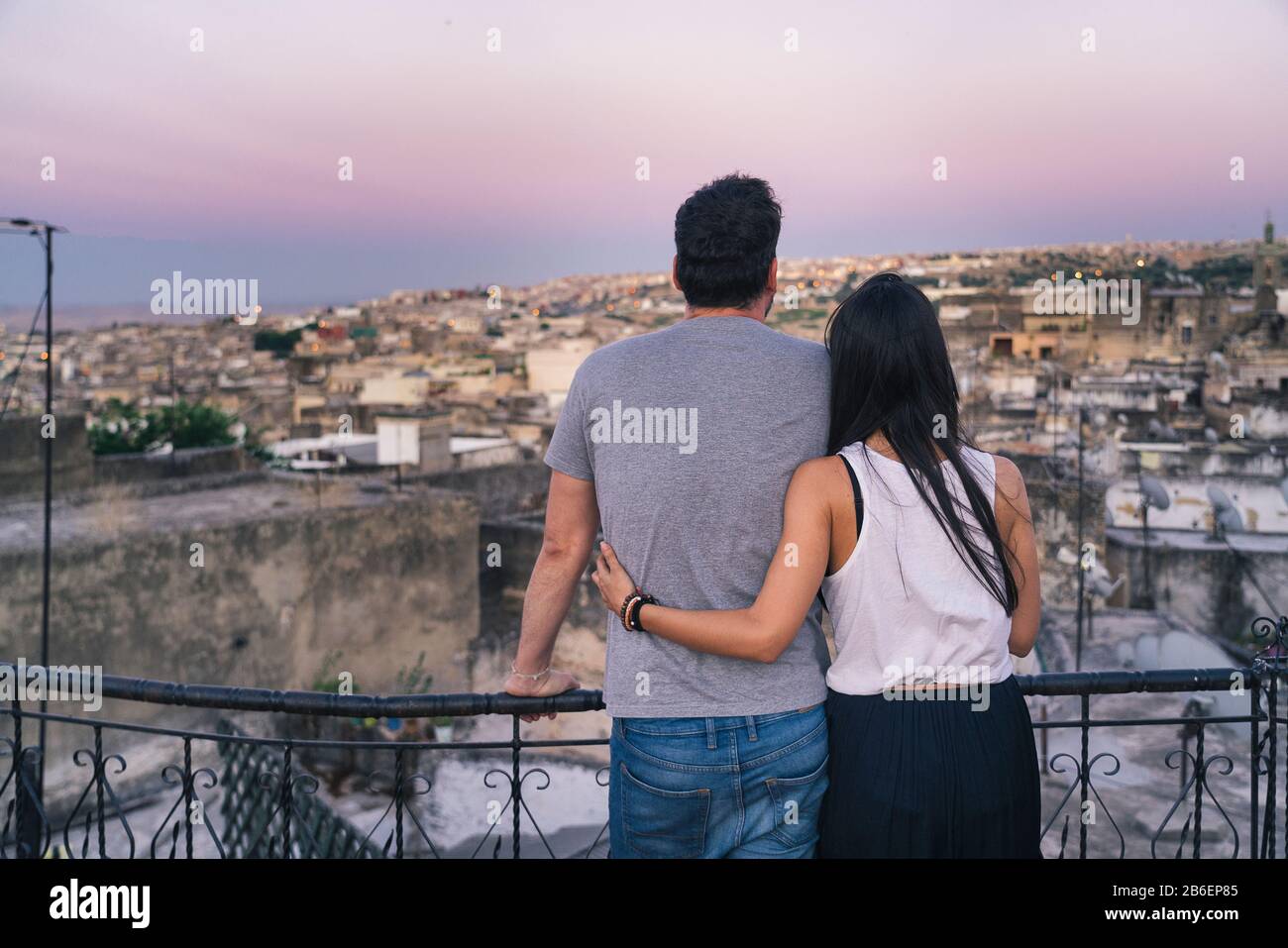 A couple enjoying the sunset of the old medina in Fez from a roof, in ...