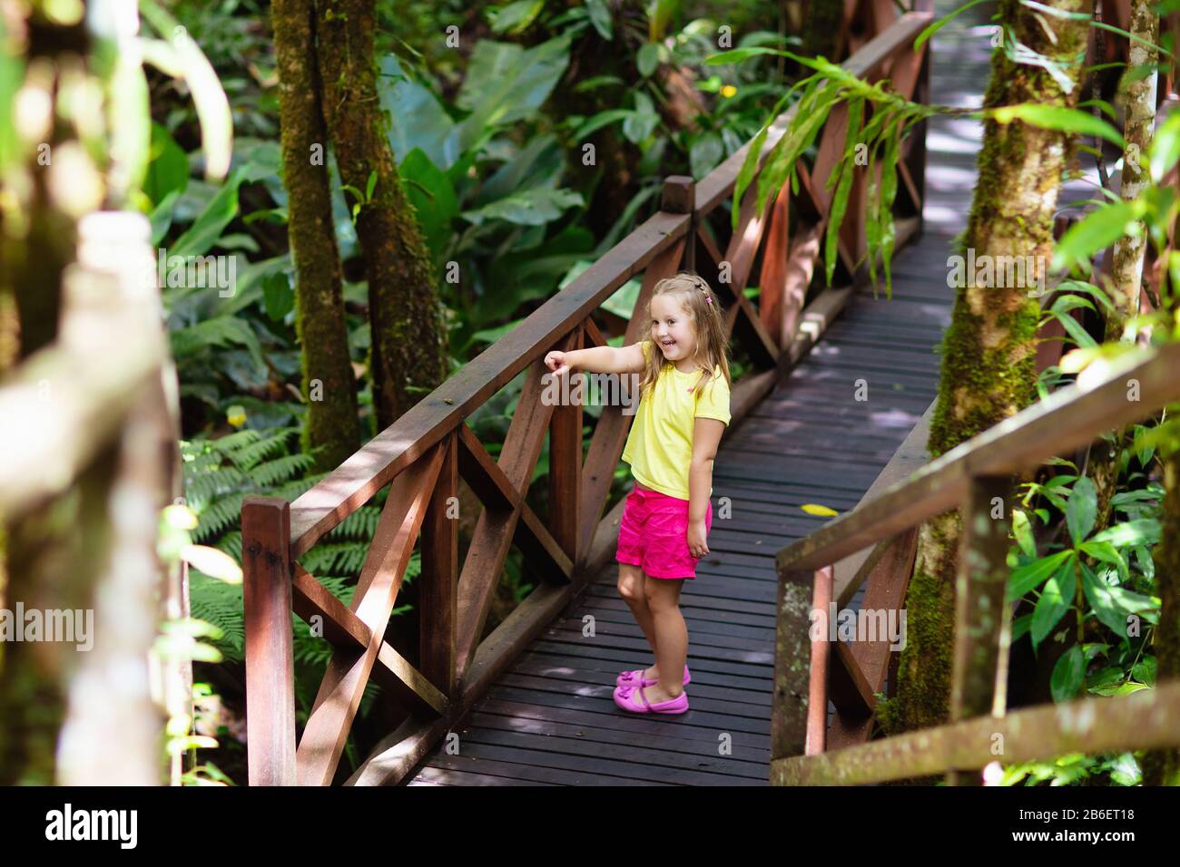 Little girl hiking in jungle. Child looking at wild orchid in tropical ...