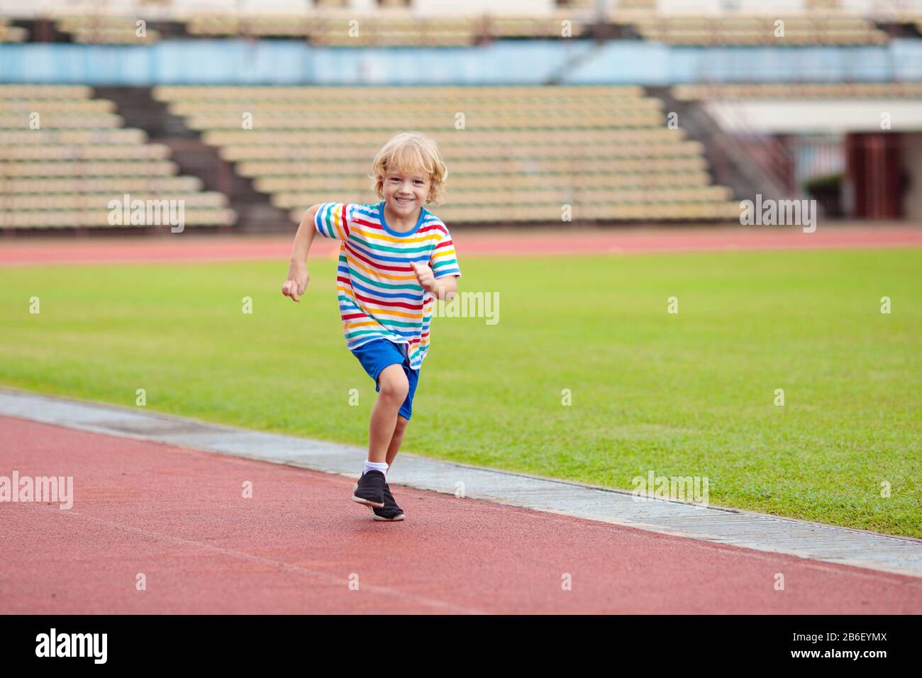Child running in stadium. Kids run on outdoor track. Healthy sport ...