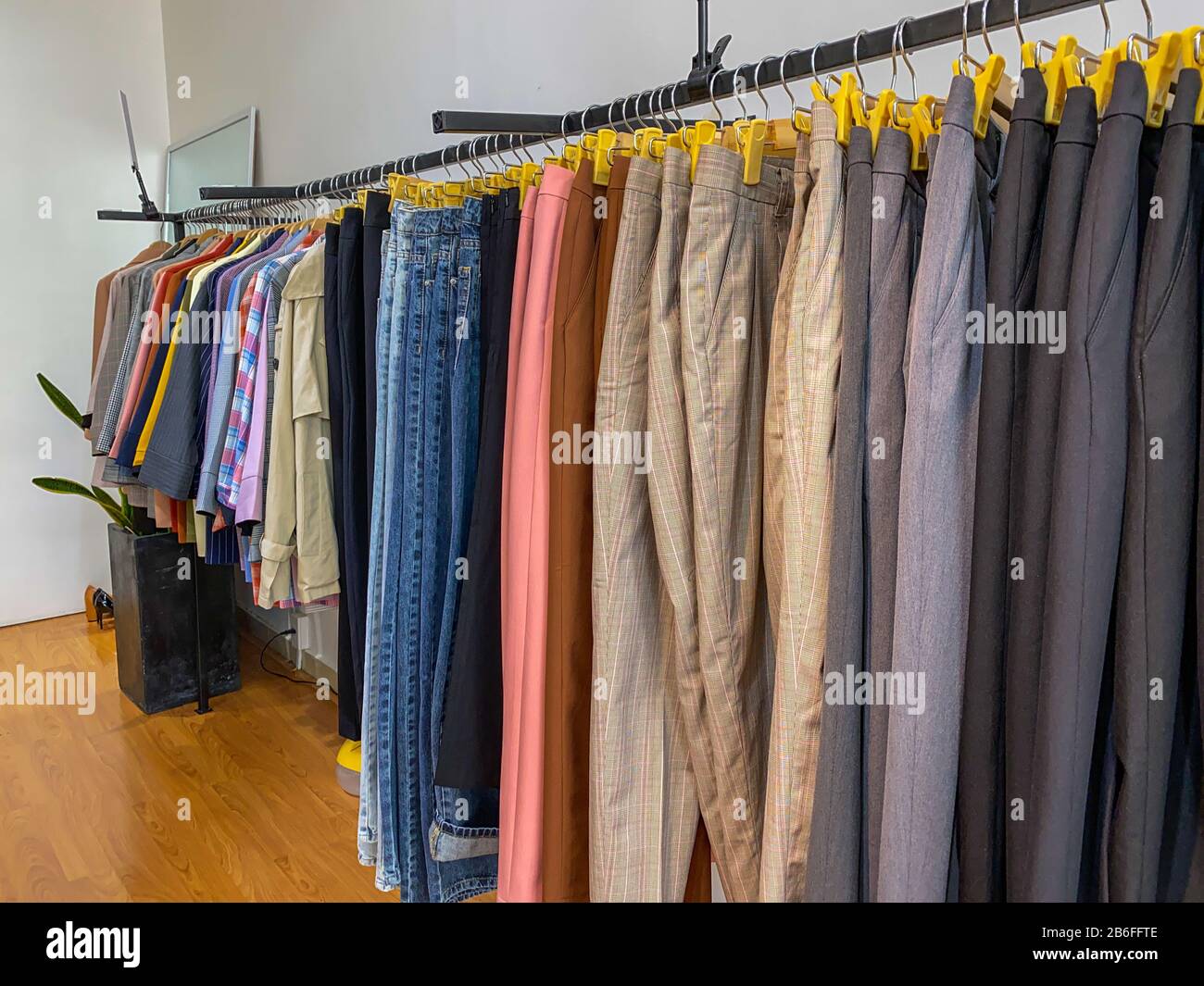 Pants and shirts hanging on shelf at clothing store Stock Photo - Alamy