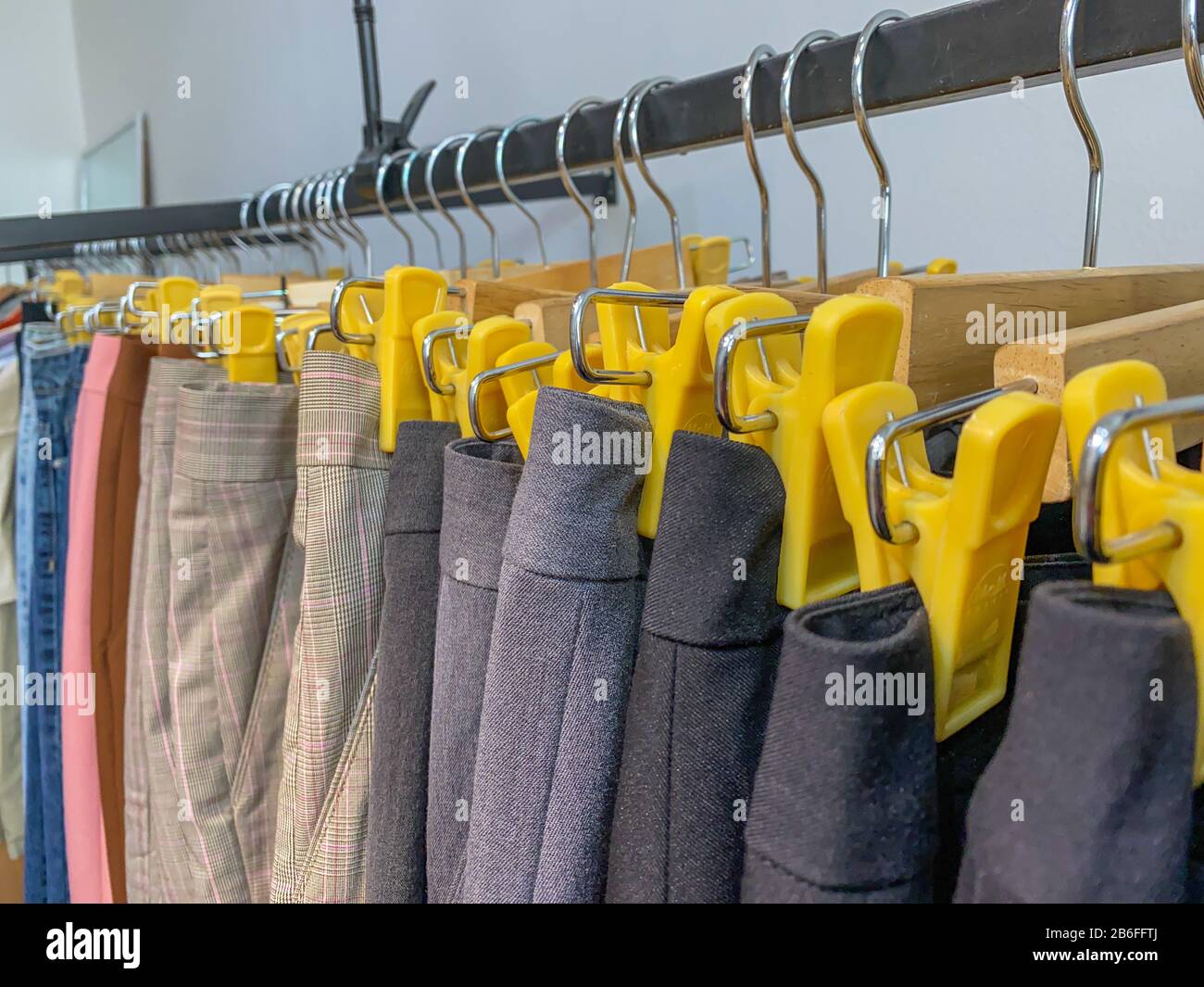 Pants hanging on shelf at retail clothing store Stock Photo - Alamy