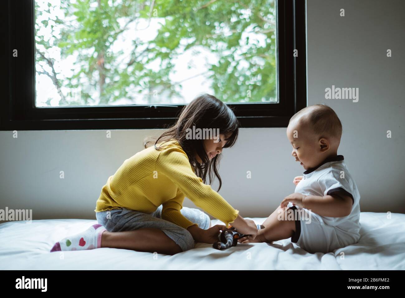 cute little brother and sister interaction on the bed Stock Photo - Alamy