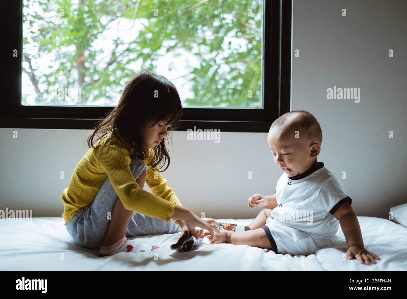 cute little brother and sister interaction on the bed Stock Photo - Alamy