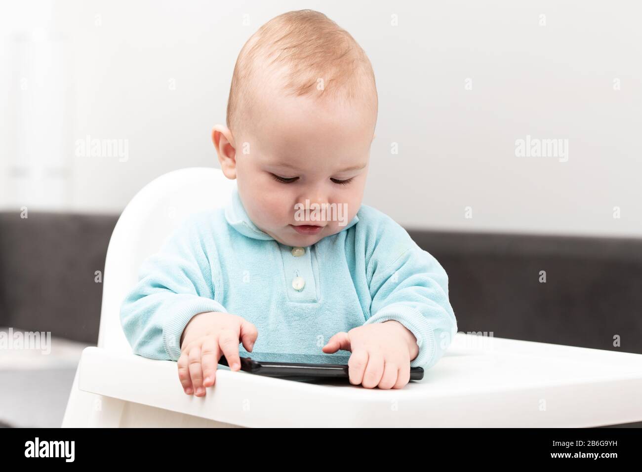 Baby Child In Chair And Playing With Mobile Phone Stock Photo - Alamy