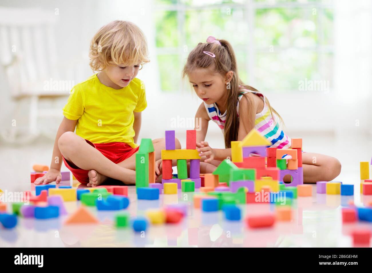 Kids play with colorful blocks. Little boy and girl build tower at home ...
