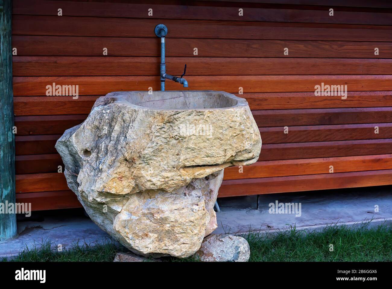 An outdoor basin carved out of rock with a tap for washing hands and ...
