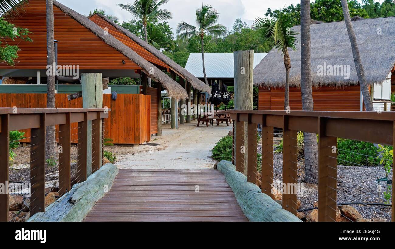 A timber boardwalk entry into a tropical resort in landscaped gardens ...