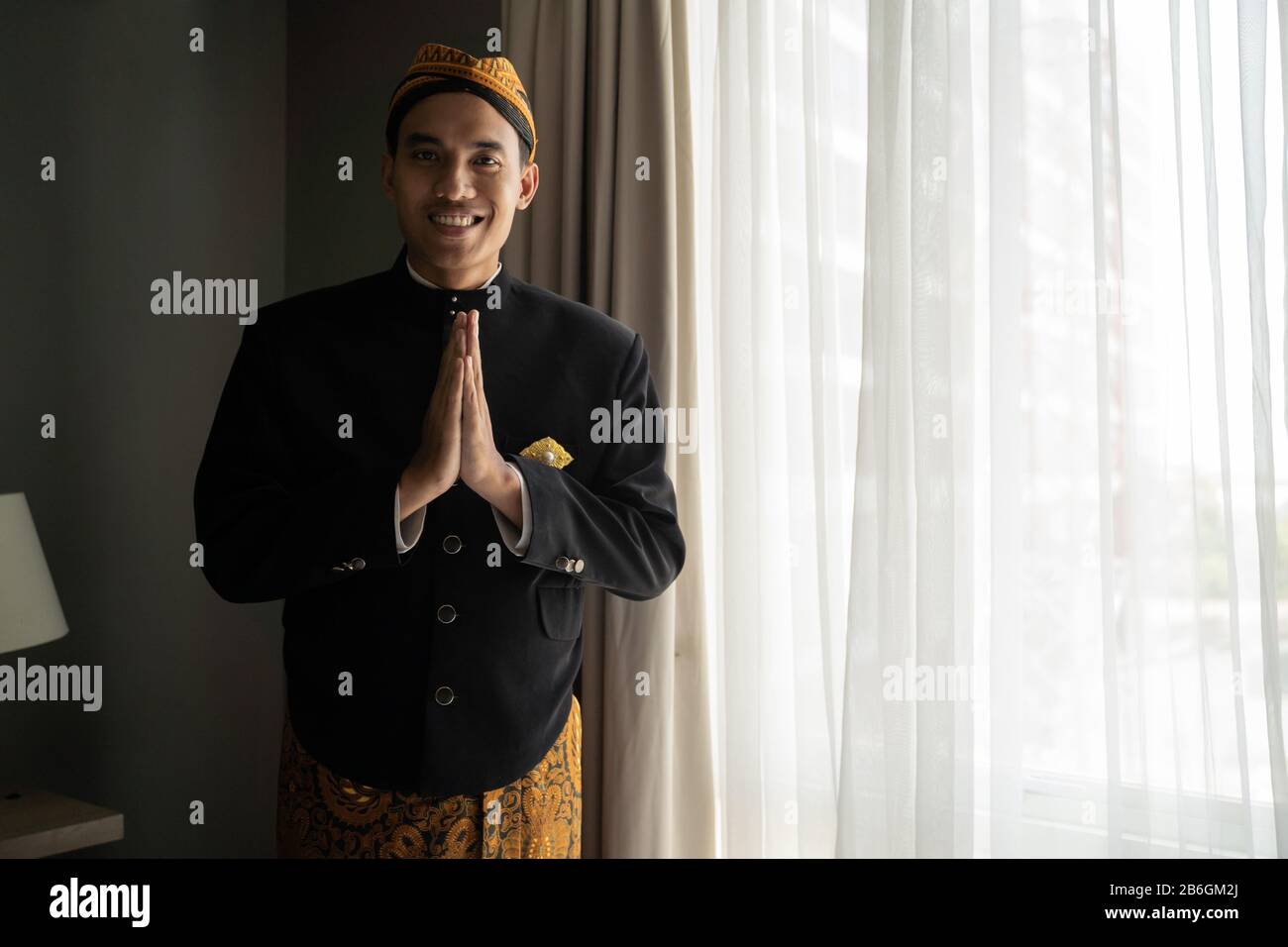Asian man wearing traditional clothes with welcome gesture,beskap is ...