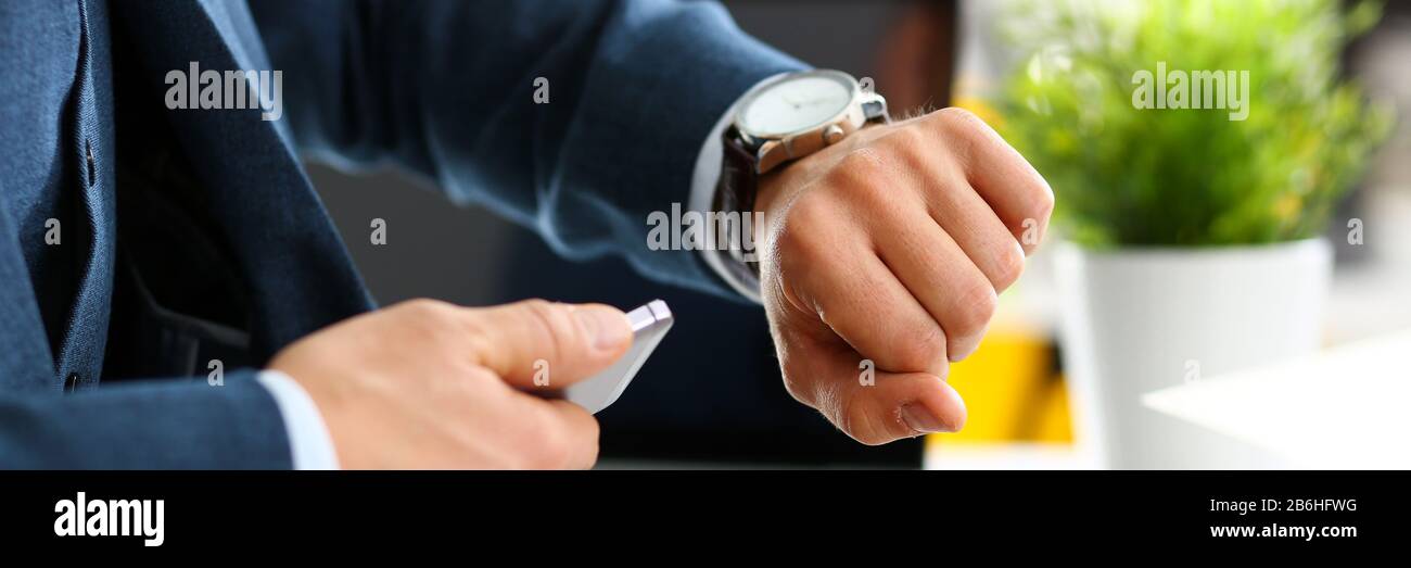 Man in suit and tie check out time at silver wristwatch Stock Photo - Alamy