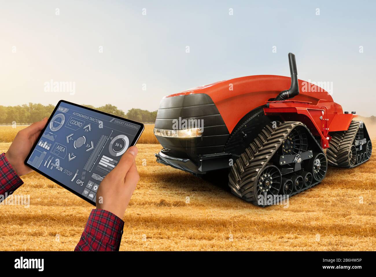 Farmer with digital tablet controls autonomous tractor on a smart farm ...